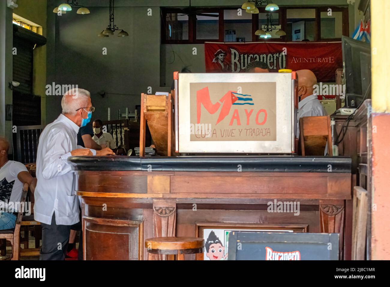 A sign with a slogan is seen in a bar counter. It reads 'May First ...