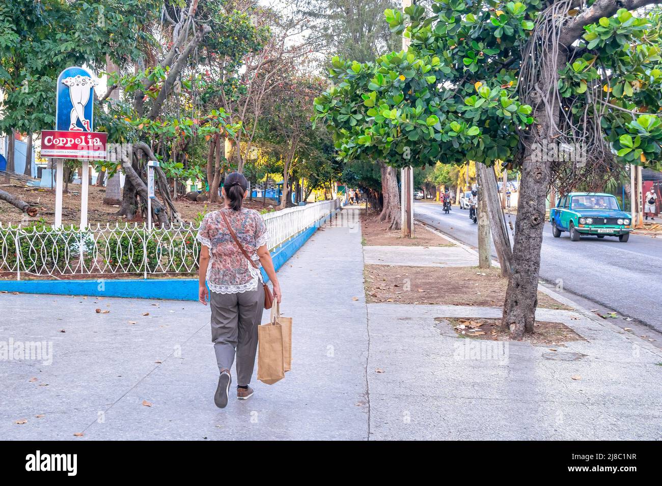 A Cuban woman holding a bag walks in the sidewalk of El Coppelia in El ...