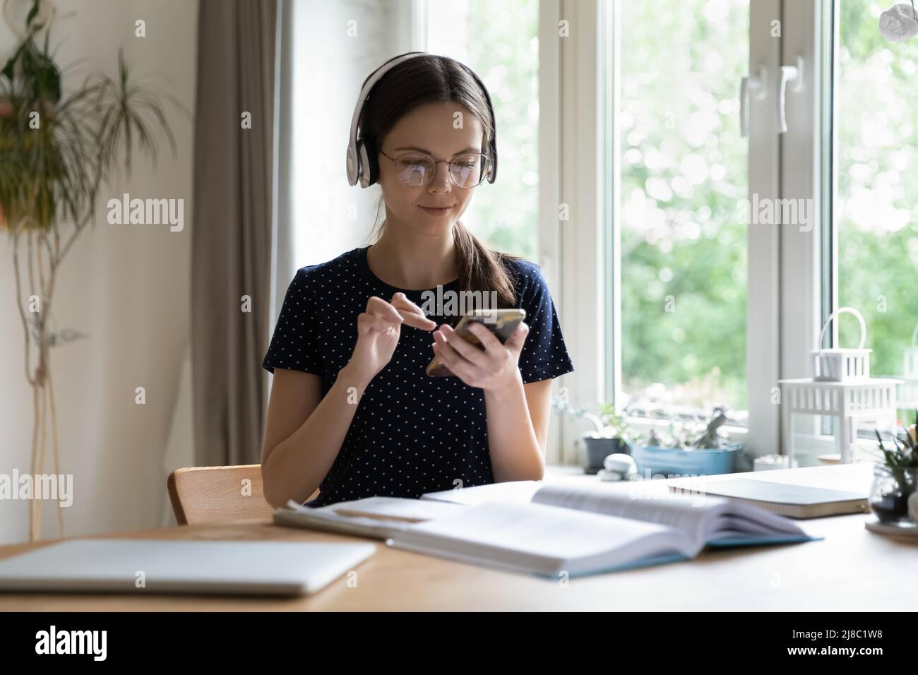 Focused smart student girl in wireless headphones using learning app ...