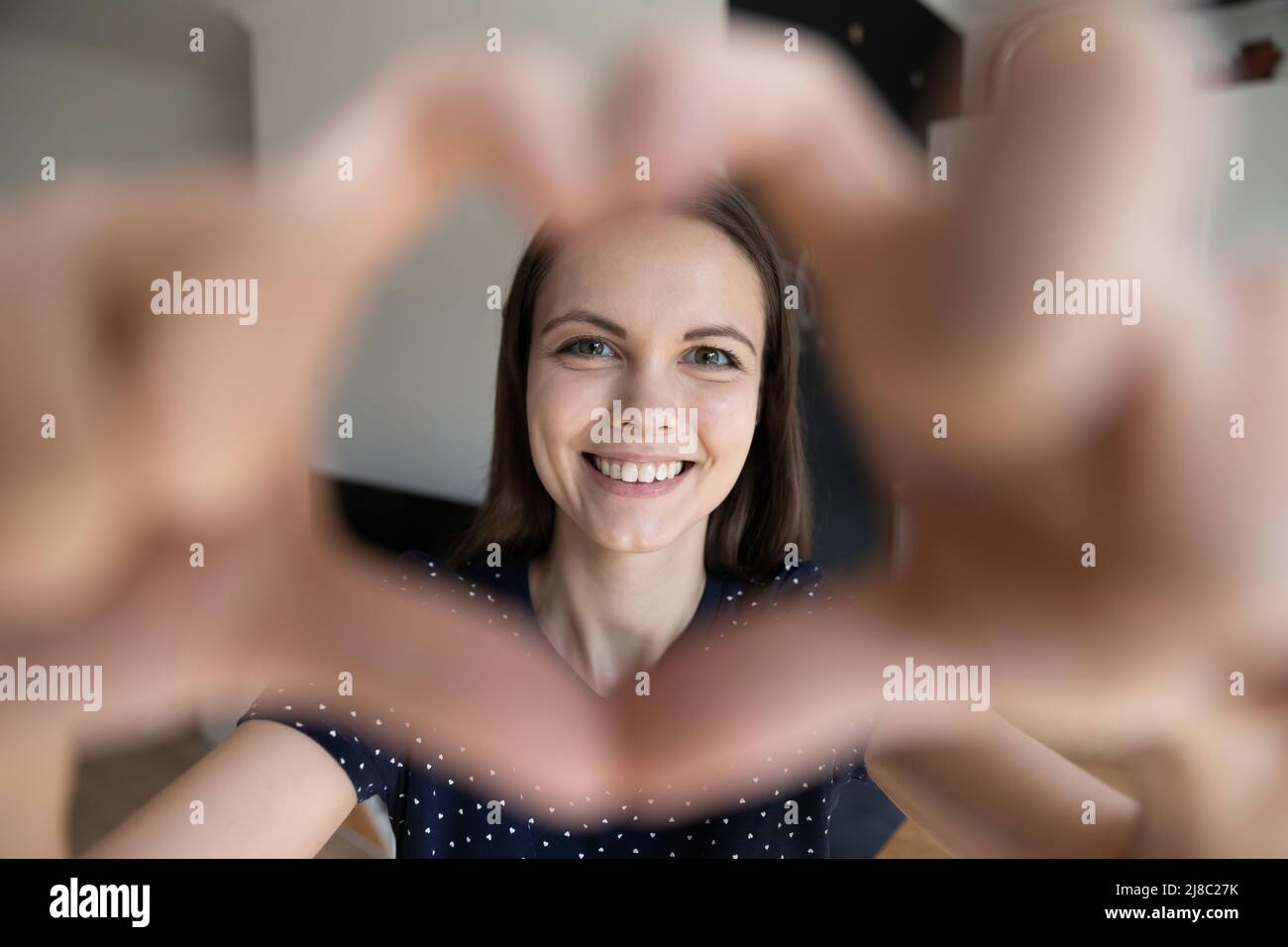 Happy pretty young woman smiling through hand heart shaped frame Stock ...