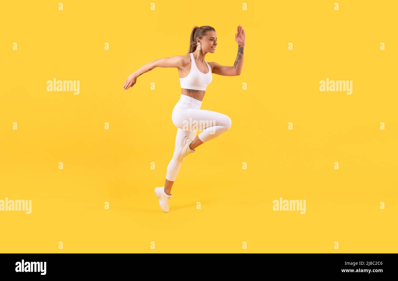 energetic fitness girl runner running on yellow background Stock Photo ...
