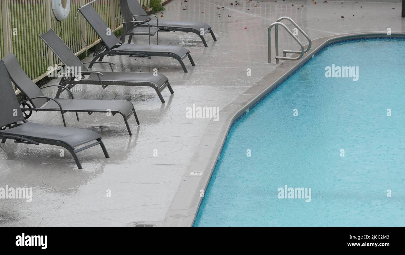 Rain drops falling on water surface of blue swimming pool, rainy day in ...