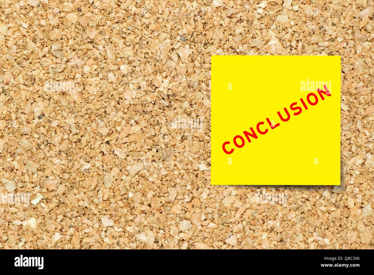 Yellow note paper with word conclusion on cork board background with ...
