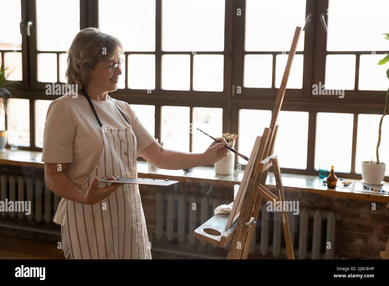Mature painter woman painting on canvas smiles enjoy creative hobby ...