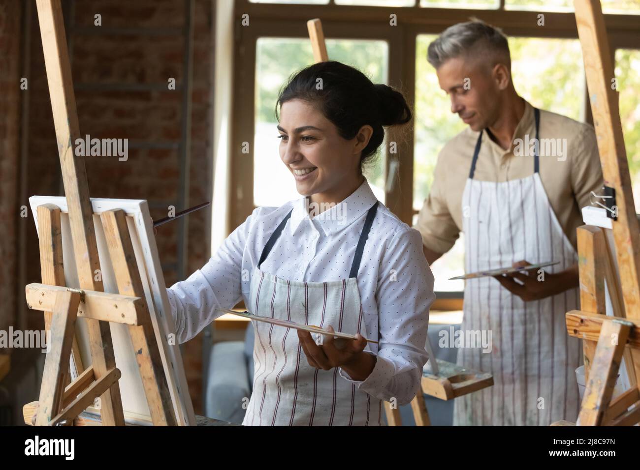 Indian painter woman painting on canvas during group artistic class ...