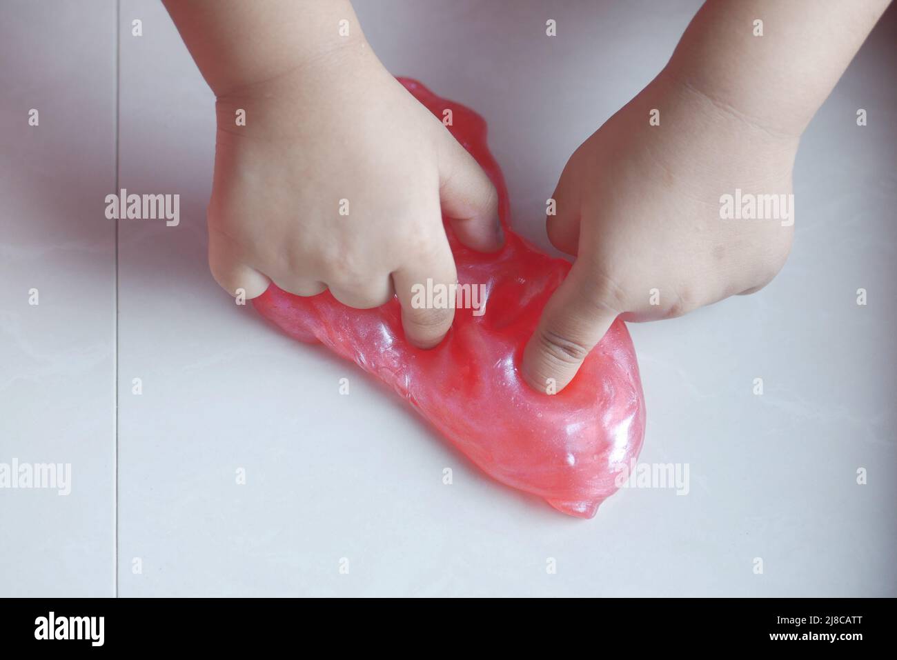 child Hand holding slime on tiles floor top view Stock Photo - Alamy