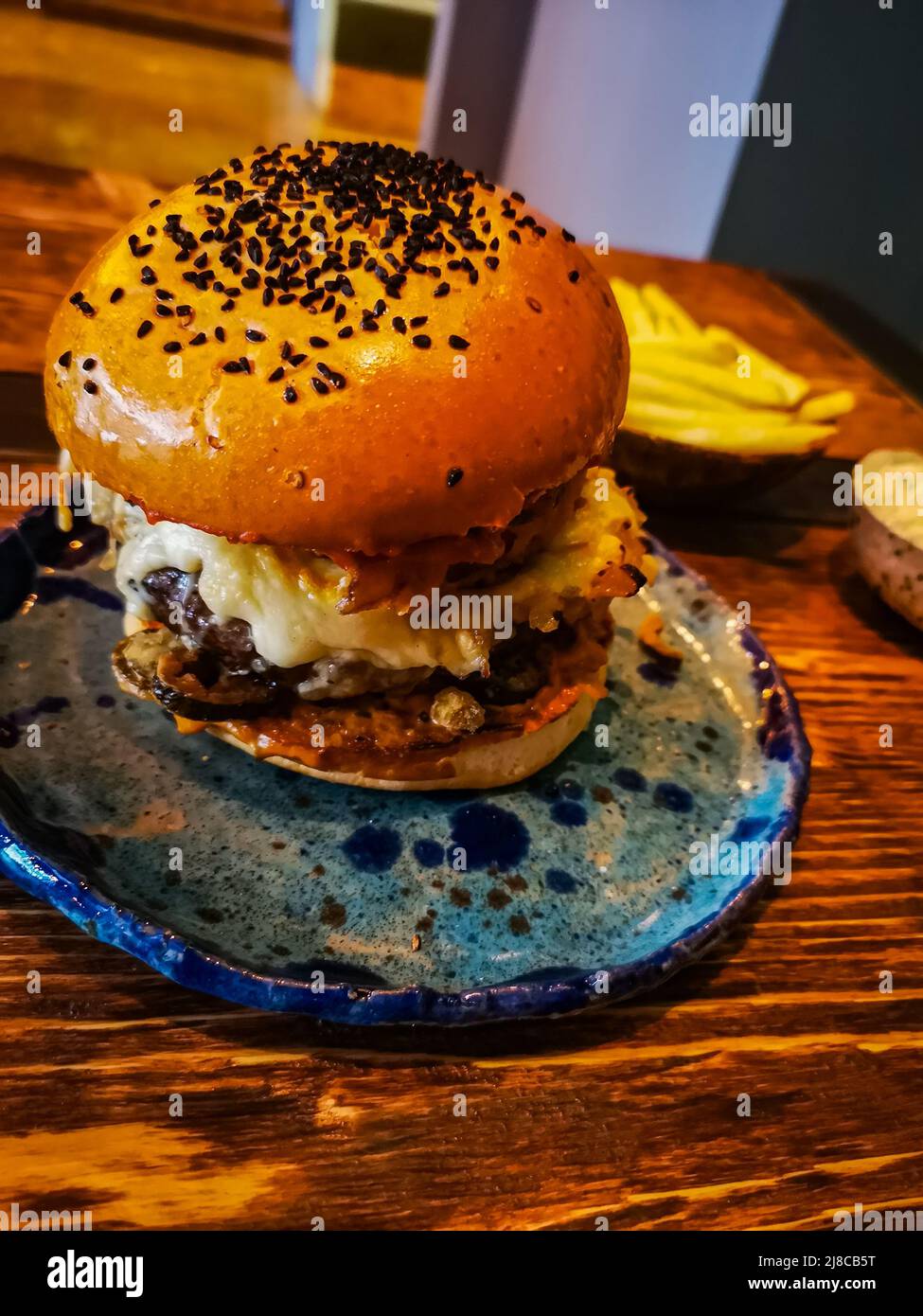 Tall burger with jalapeno peppers and black cumin on a bun lie on a ...