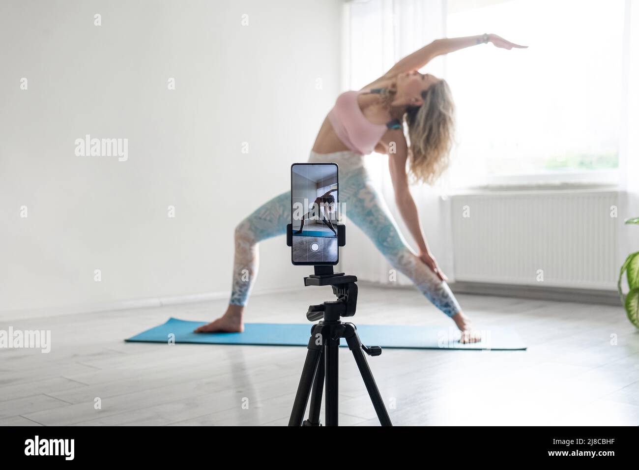 woman practicing yoga poses stretching in front of phone camera sport ...
