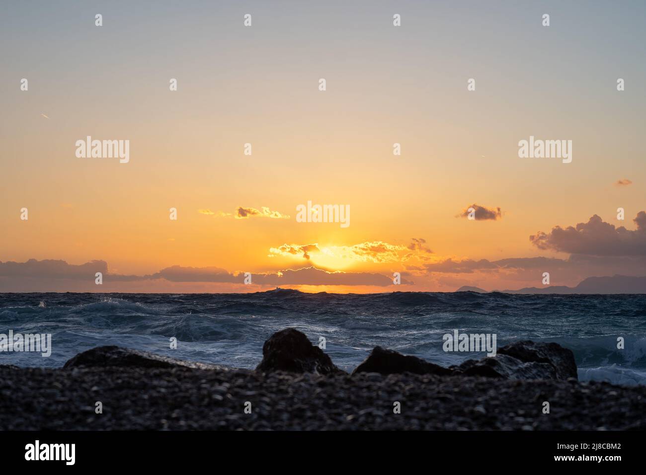 Sea wave at sunset hitting rock on the beach Stock Photo - Alamy