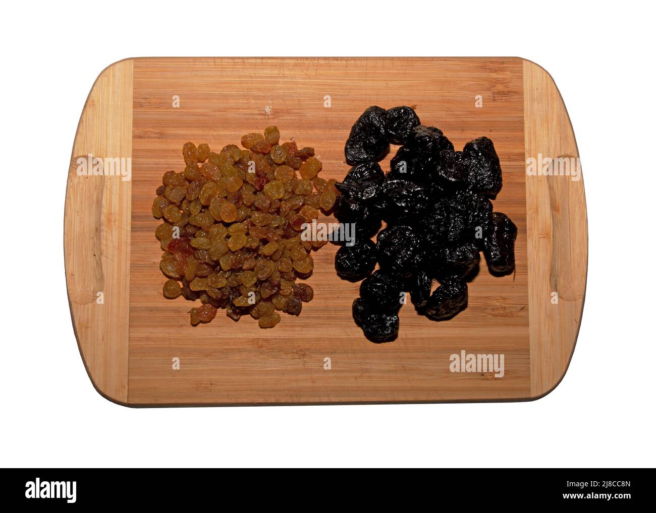 A handful of dried raisins and prunes on a wooden kitchen board ...