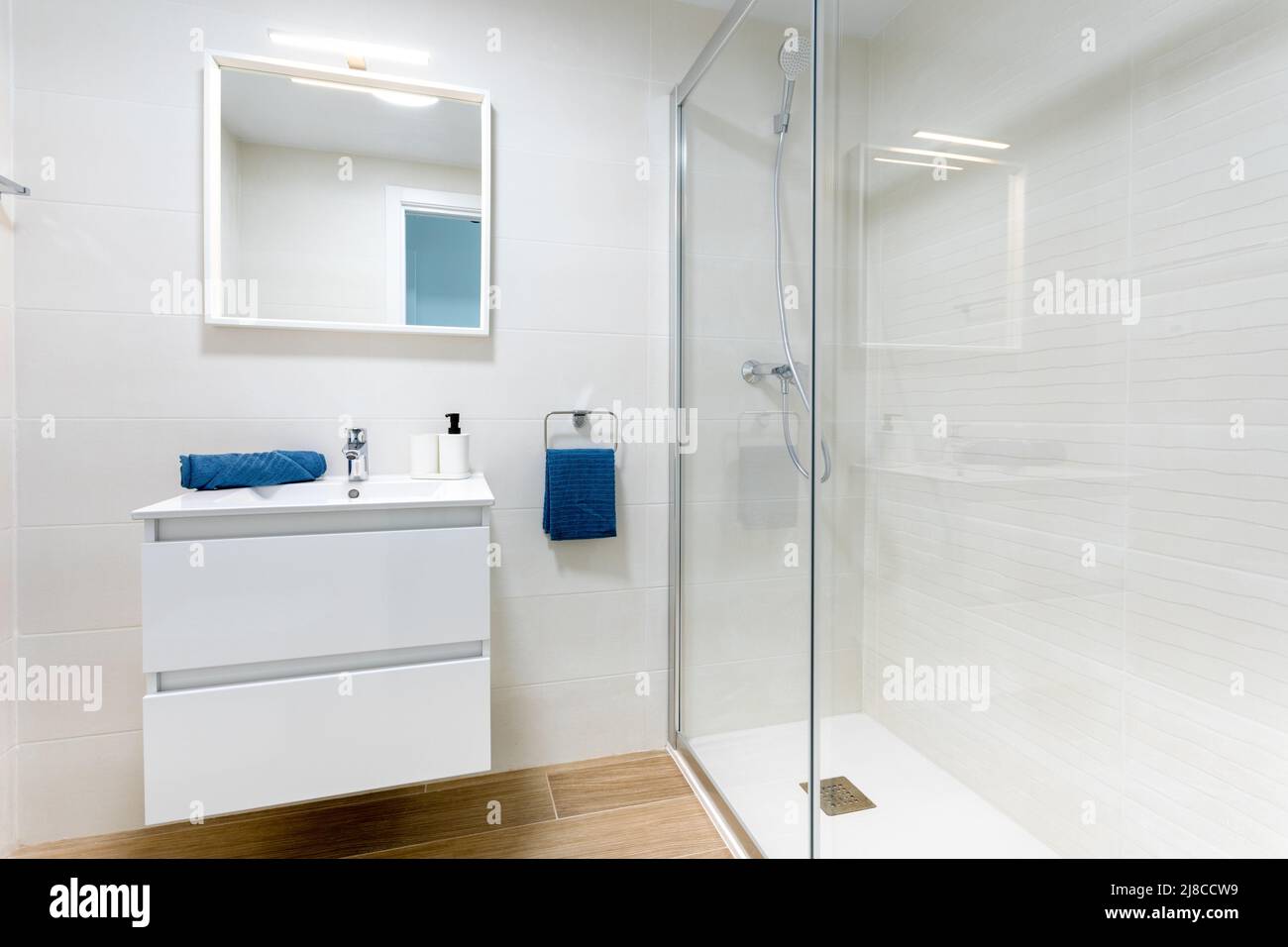 A modern, minimalist, white bathroom with a shower Stock Photo - Alamy