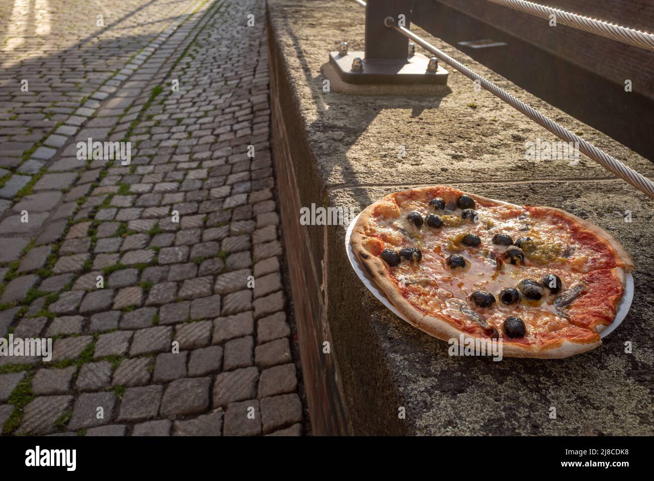 Pizza napoli style with olive and anchovy fish leave on stone fence ...