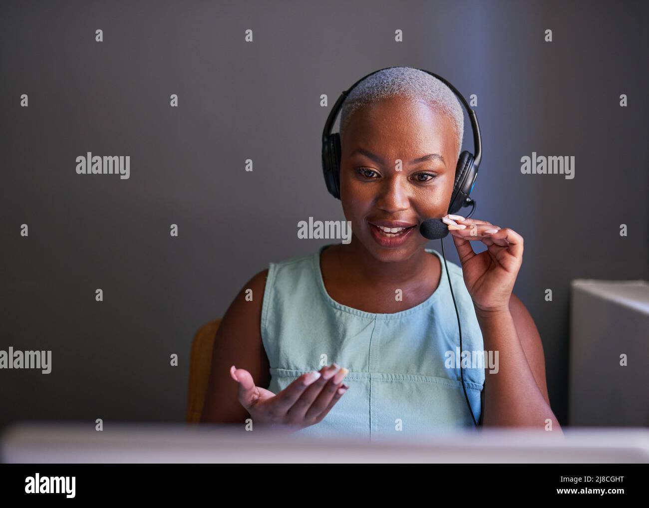 A young Black call centre agent explains patiently on a call with ...