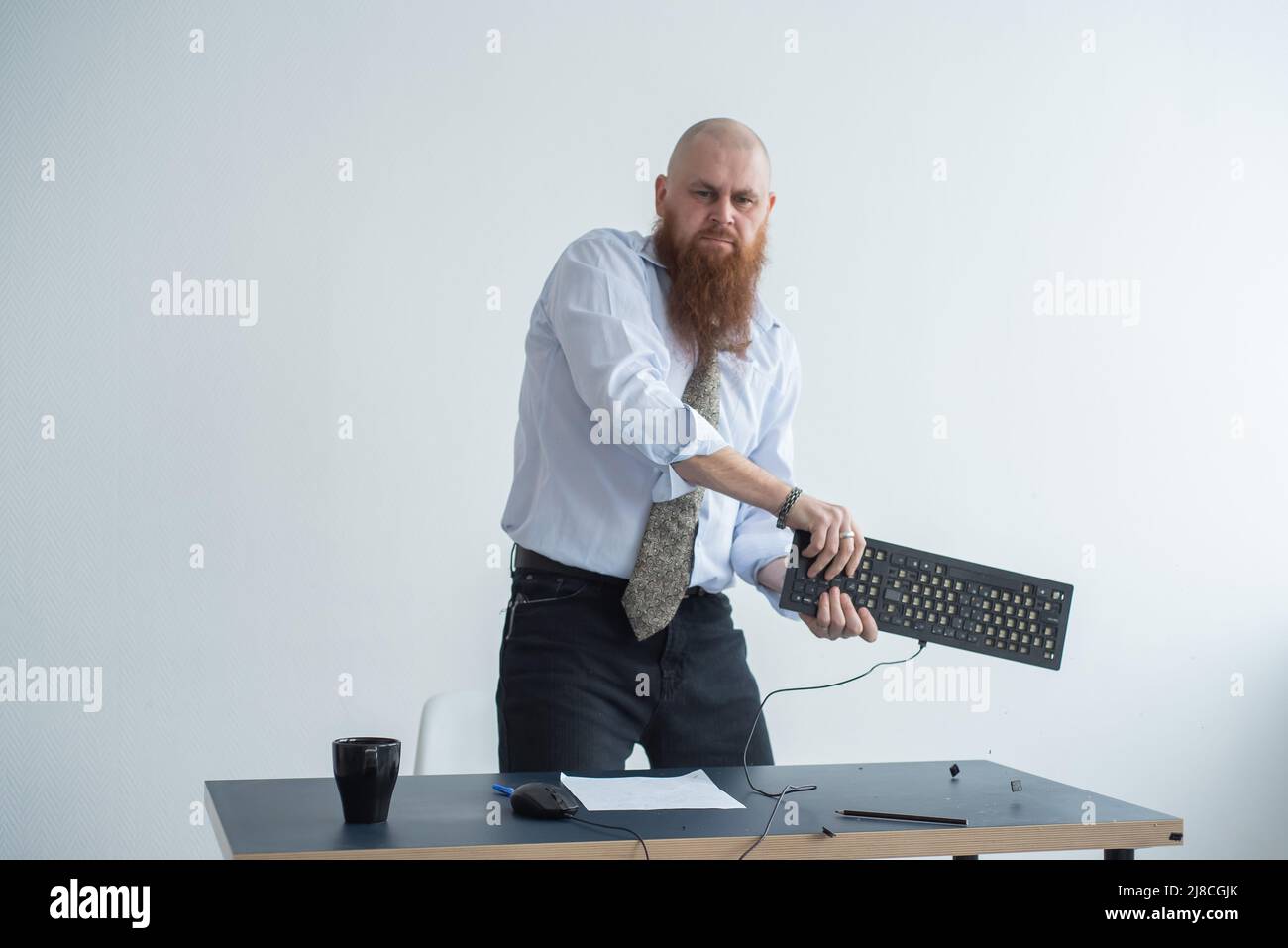 Angry bald man with a red beard in the office in a business suit ...