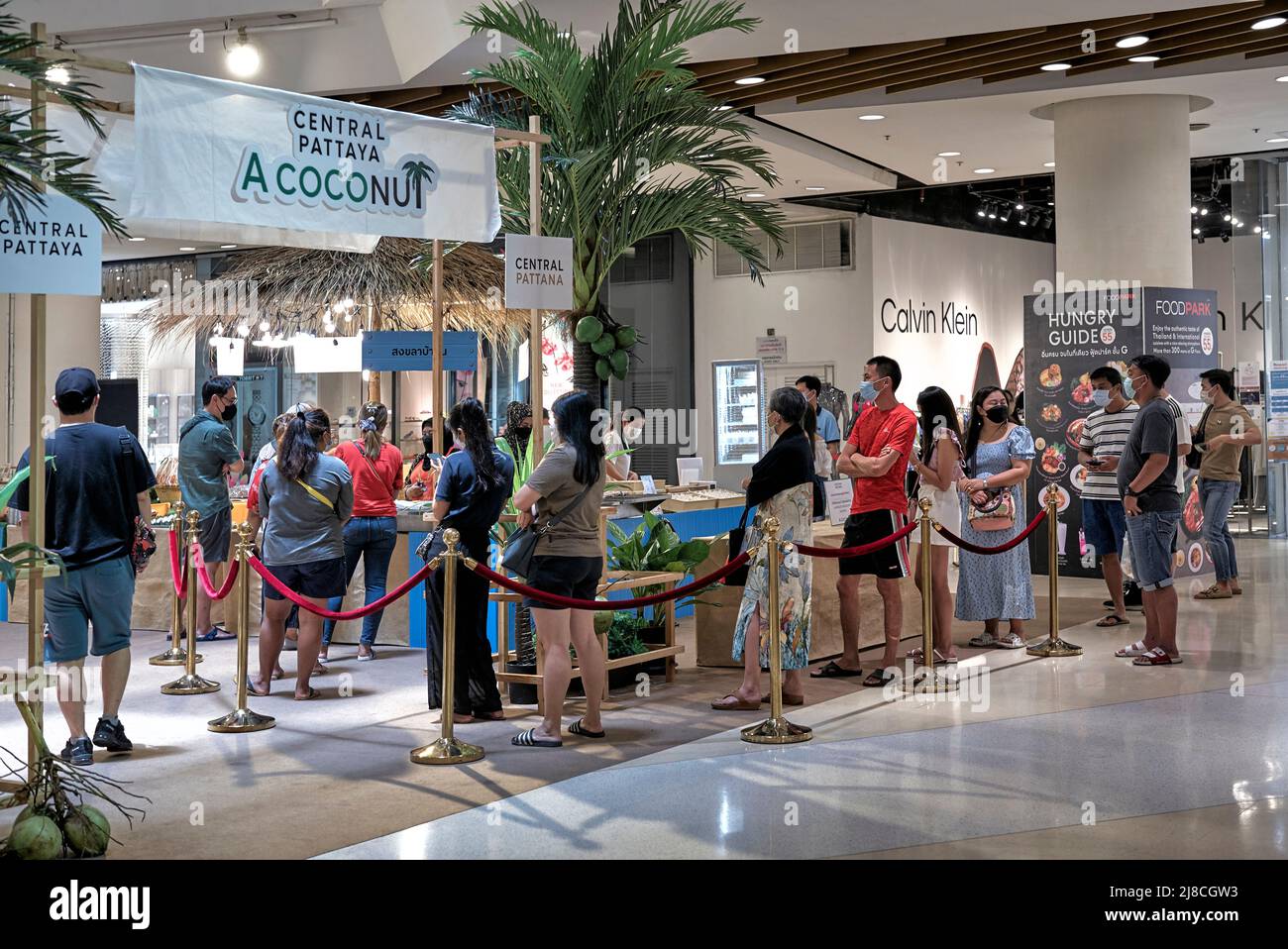 People queuing inside in a roped off cordoned area for a coconut food ...