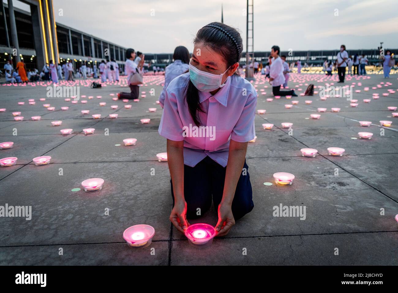 Pathum Thani, Thailand, May 15, 2022. A buddhist prays with a pink LED ...