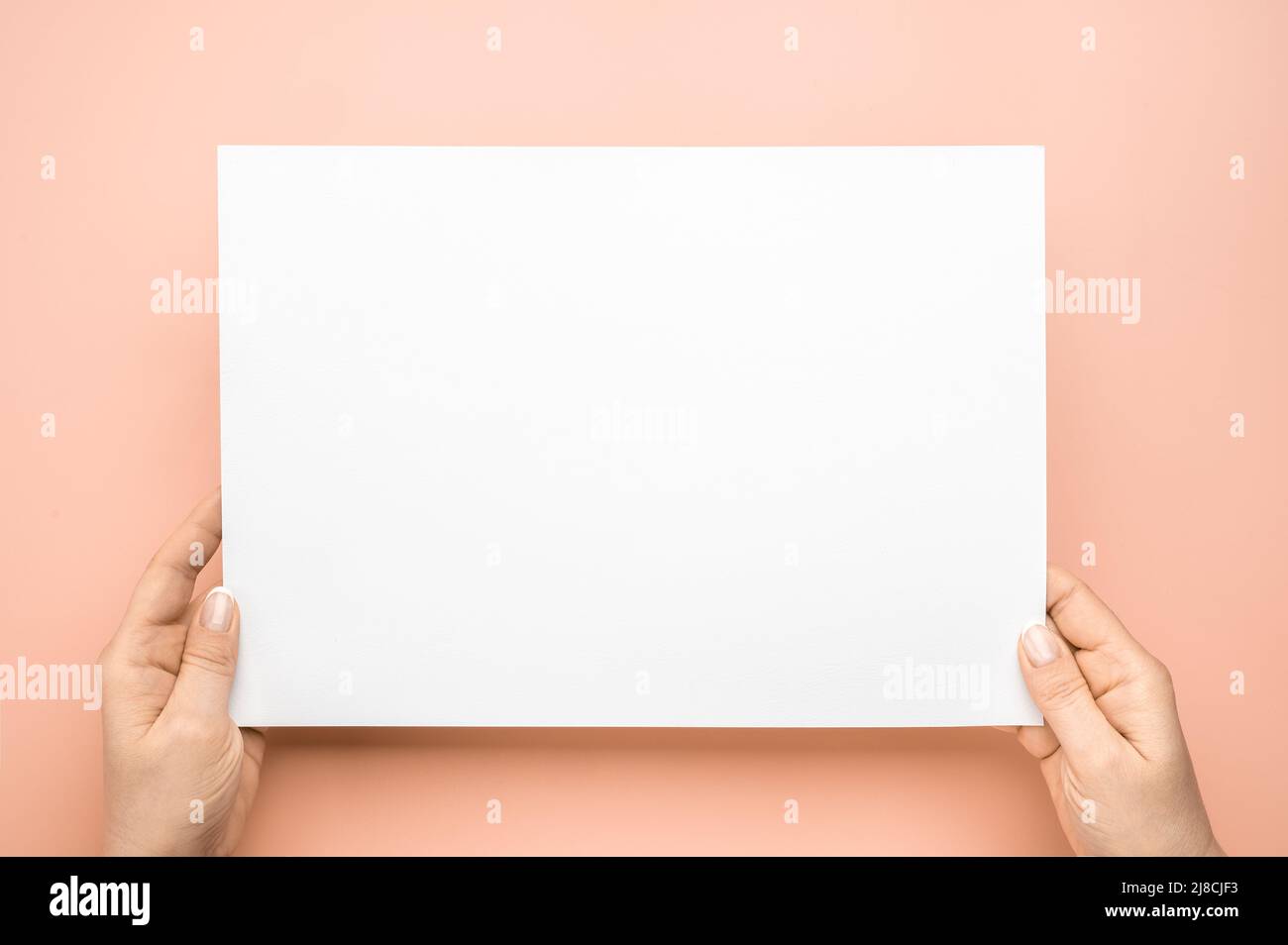 Female hands hold a blank sheet of paper on a beige background. woman ...