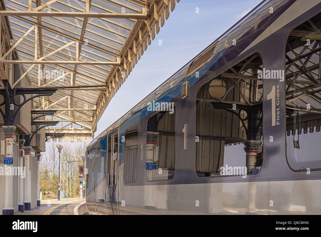 Train standing at a historic railway station platform lined by columns ...