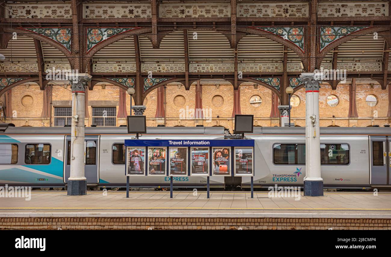Railway carriages under a historic canopy. A notice board with ...