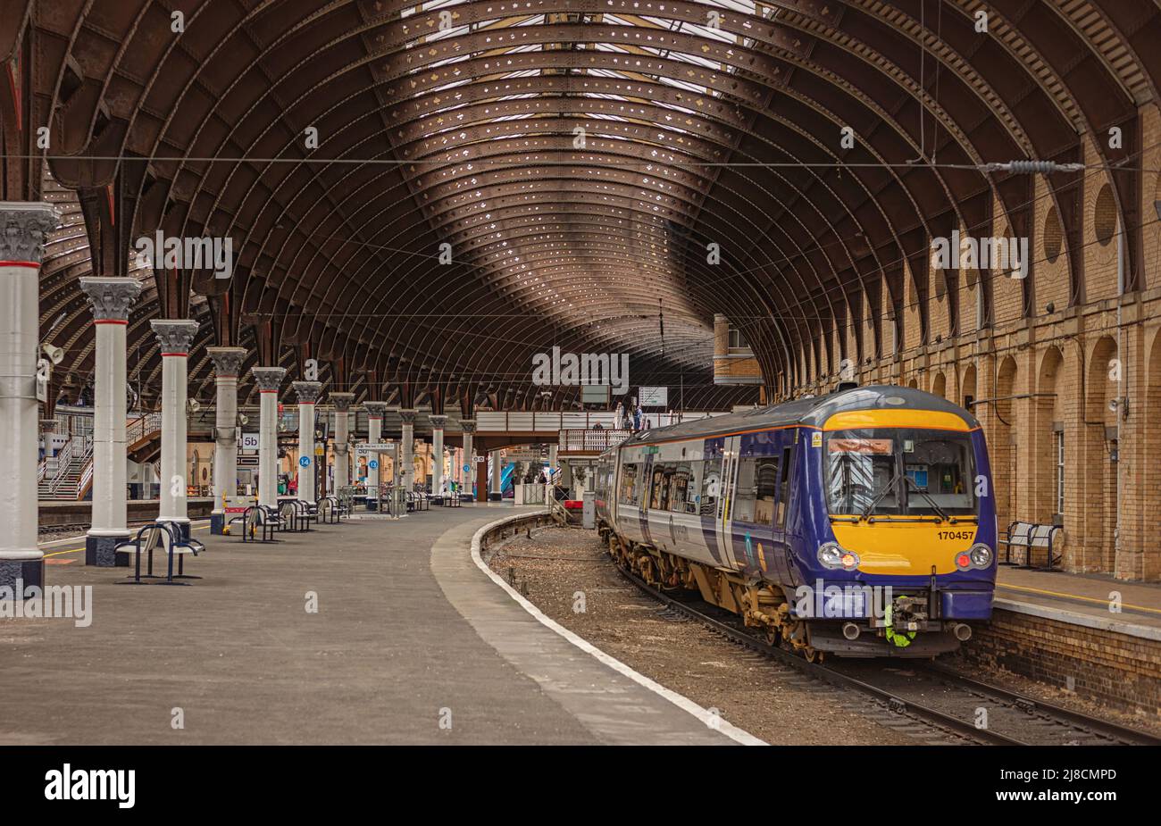 A railway station platform with a train on one side and a line of ...