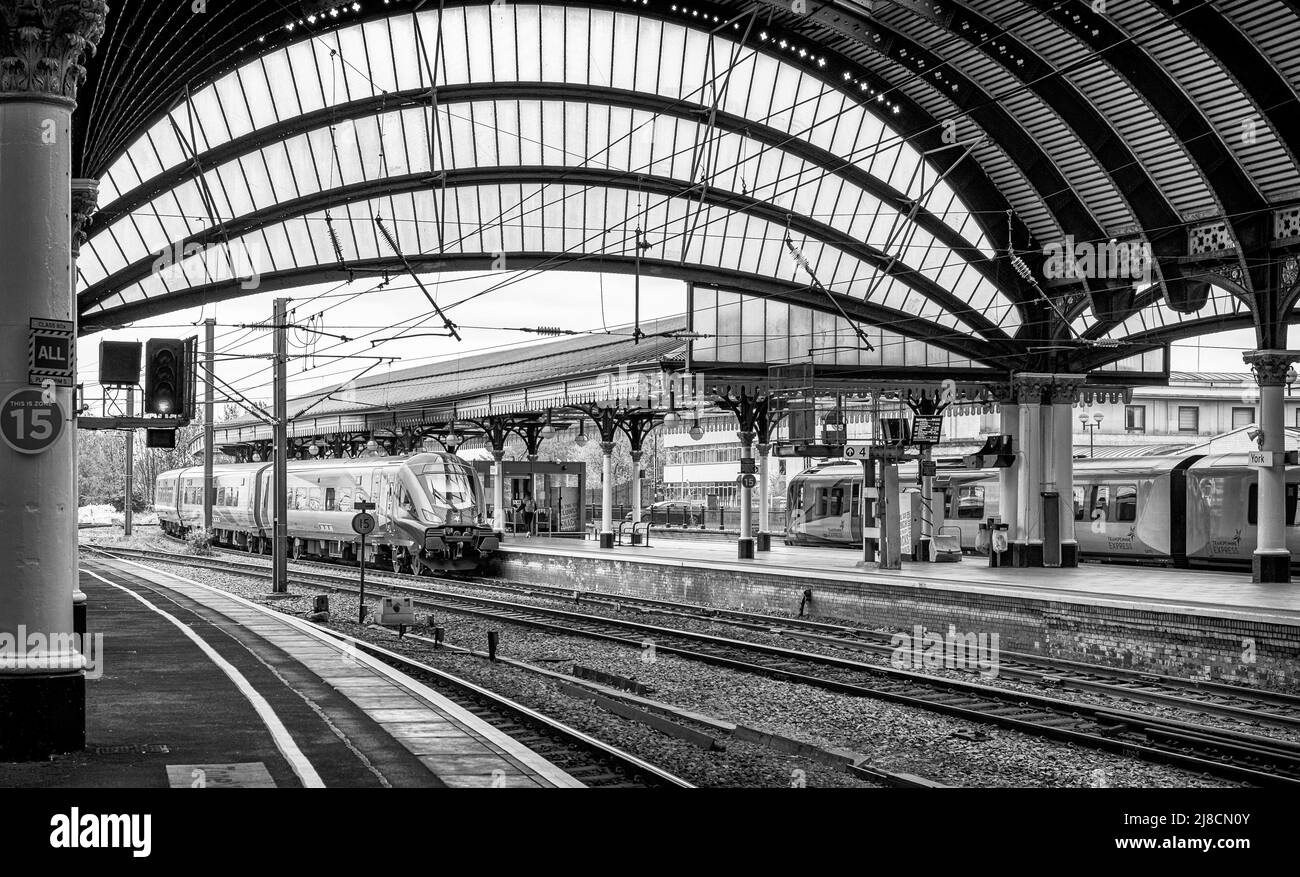 Trains stand beside a hitorical canopy viewed from under an arch ...