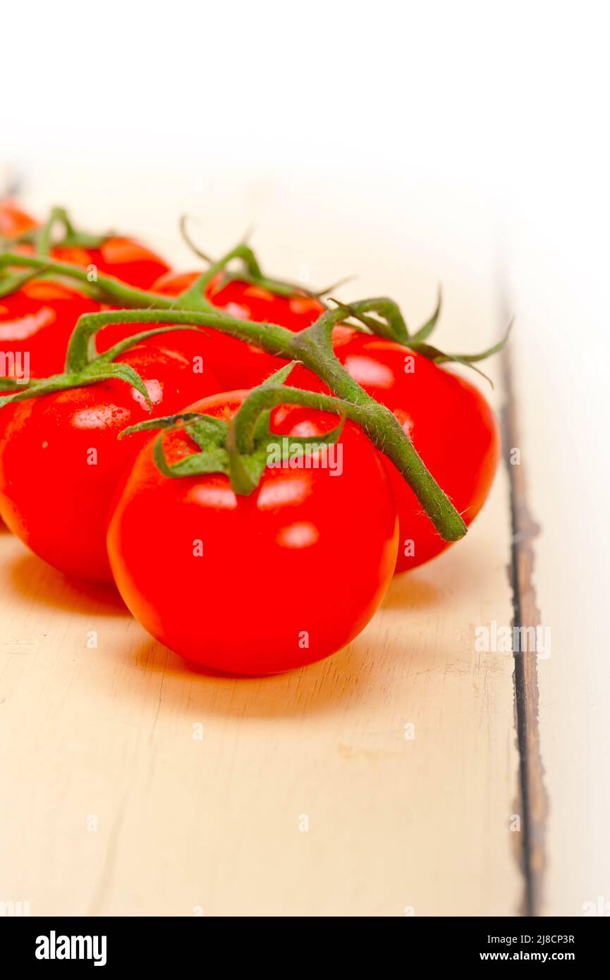 fresh cherry tomatoes on a cluster over rustic wood table Stock Photo ...