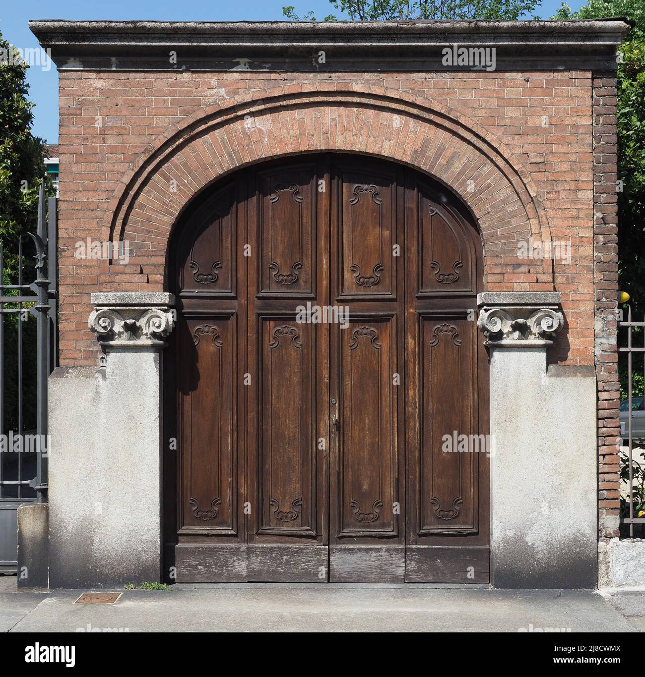 ancient wooden gate and red brick arch with columns and ionic capitals ...