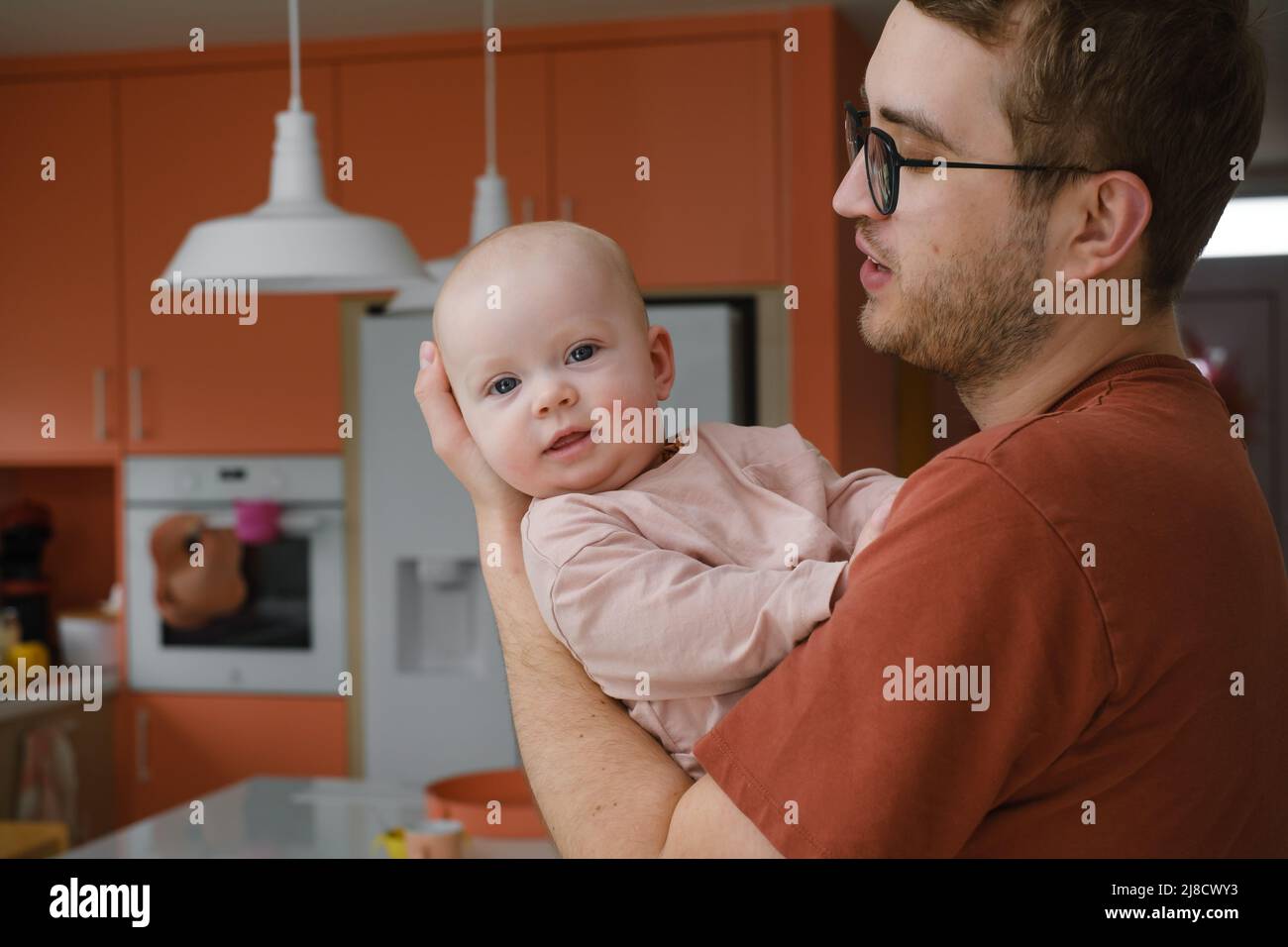 Daddy with baby girl in his hands cuddling on the kitchen at home ...