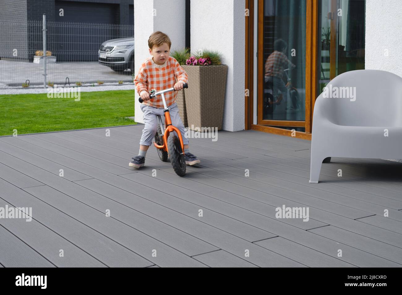 Child playing racing on bike in the home yard. Boy riding fast around ...