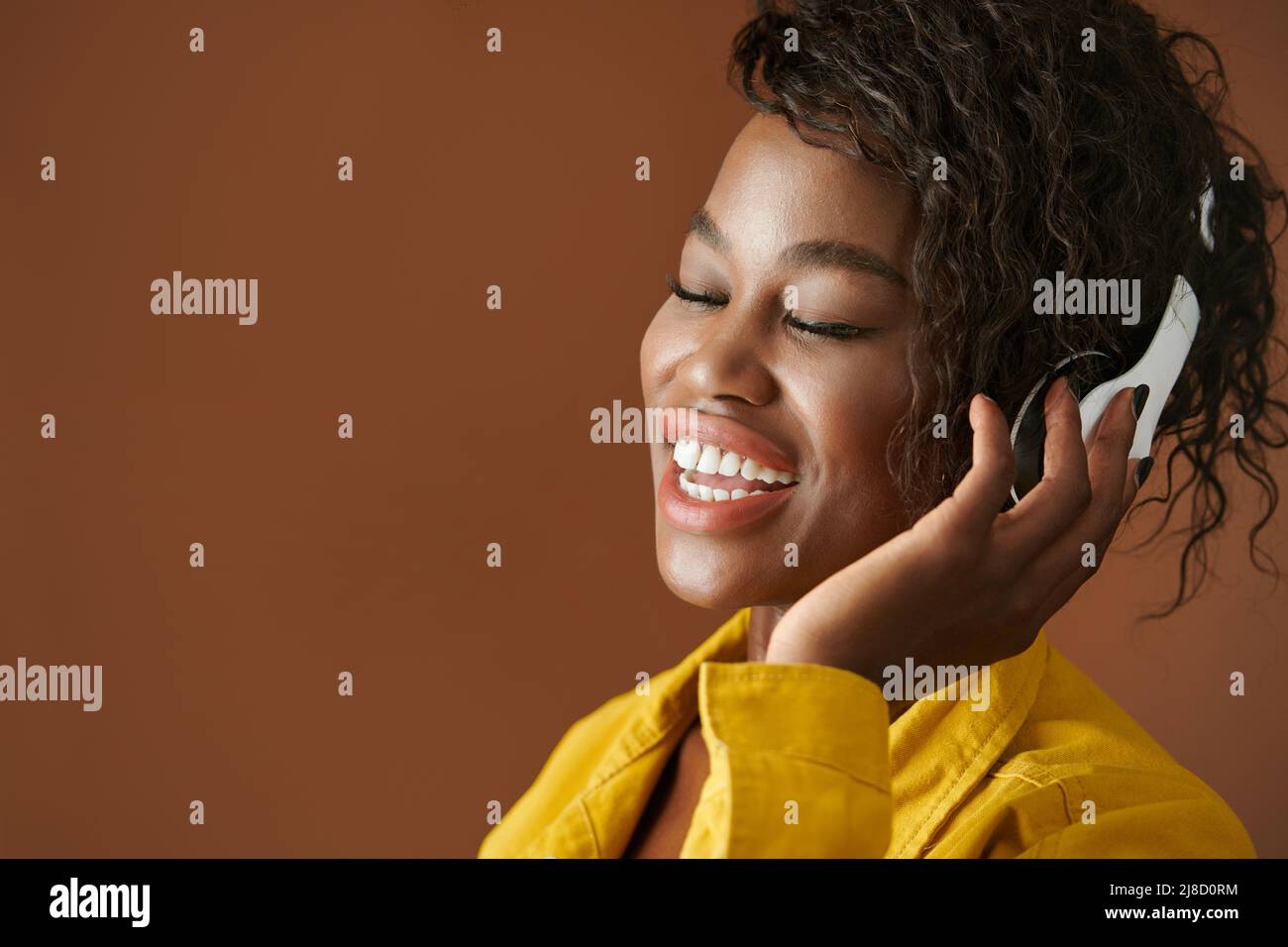Face of young Black woman enjoying good music in headphones Stock Photo ...