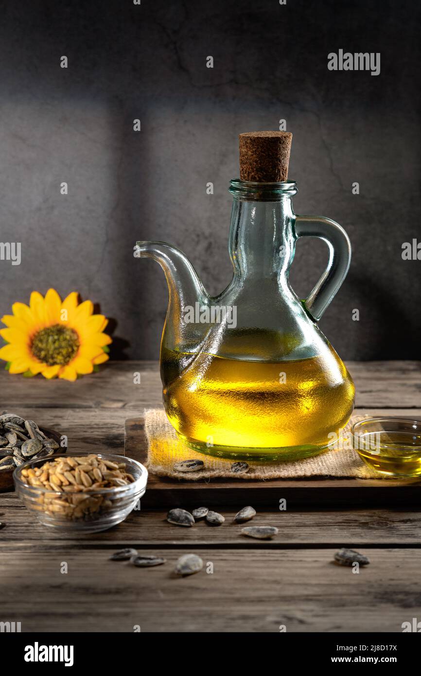 Sunflower oil and sunflower seeds on dark rustic background with ...