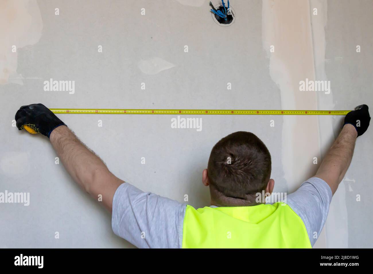 The wizard measures the distance on the wall with a tape measure Stock ...