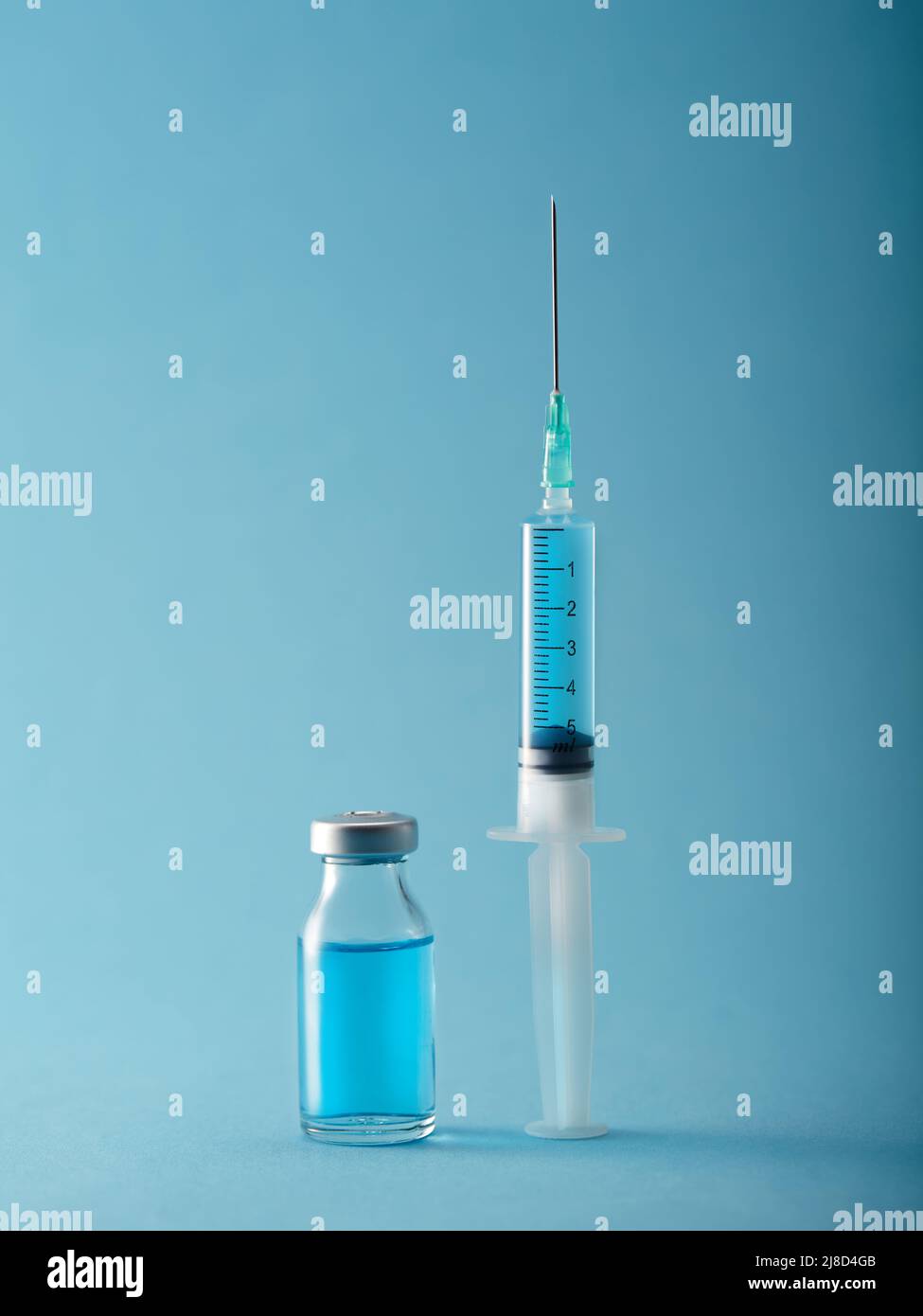 Vaccine and syringe injection on blue background. Vertical compozition ...
