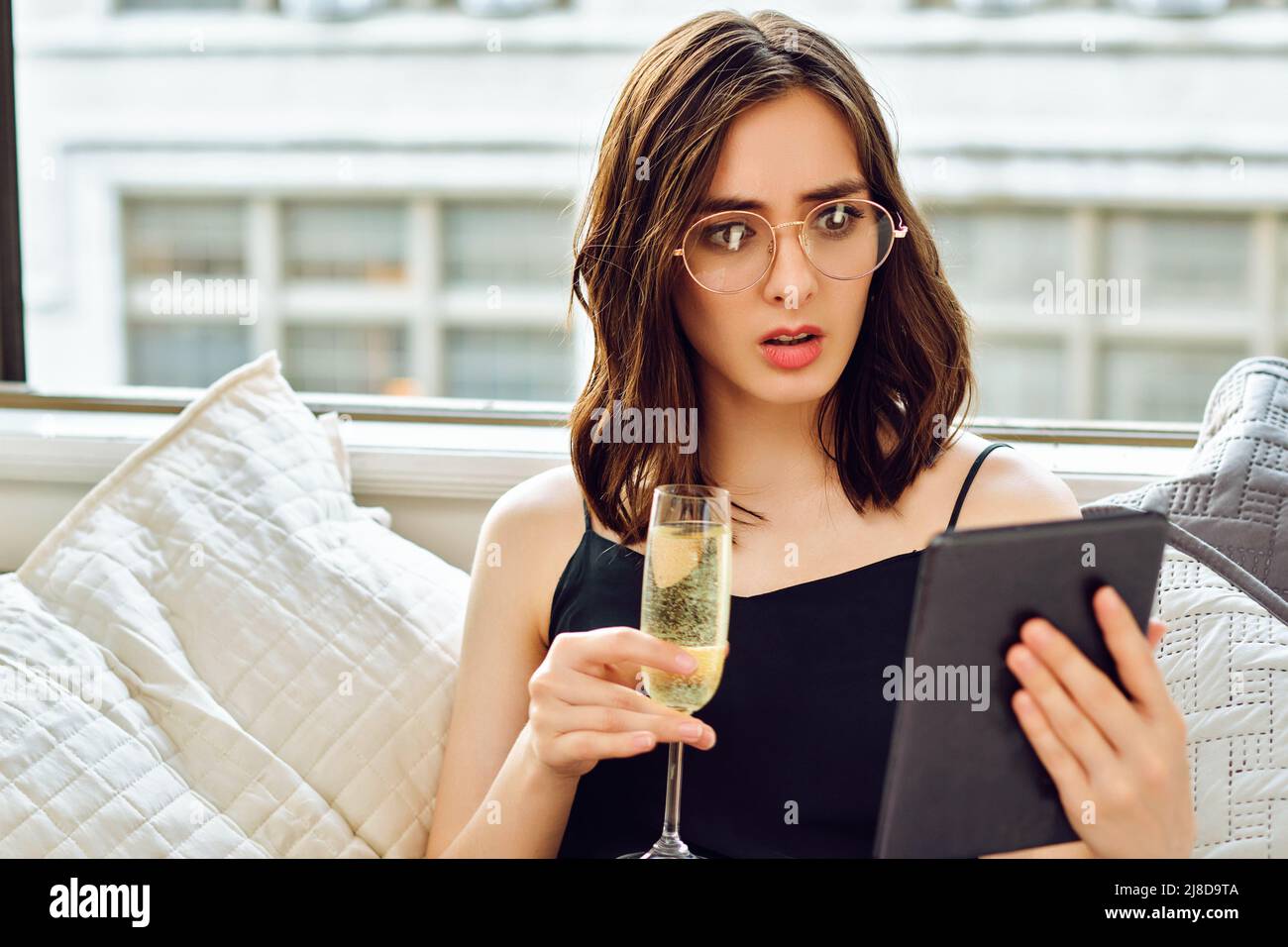 thoughtful surprised beautiful young adult woman with glass of ...