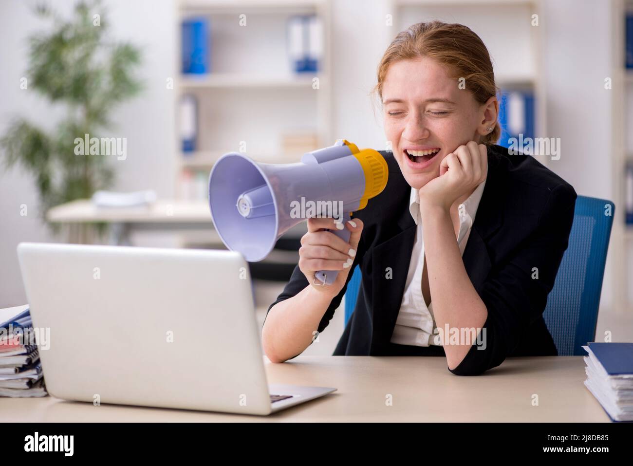 Female employee holding megaphone at workplace Stock Photo - Alamy