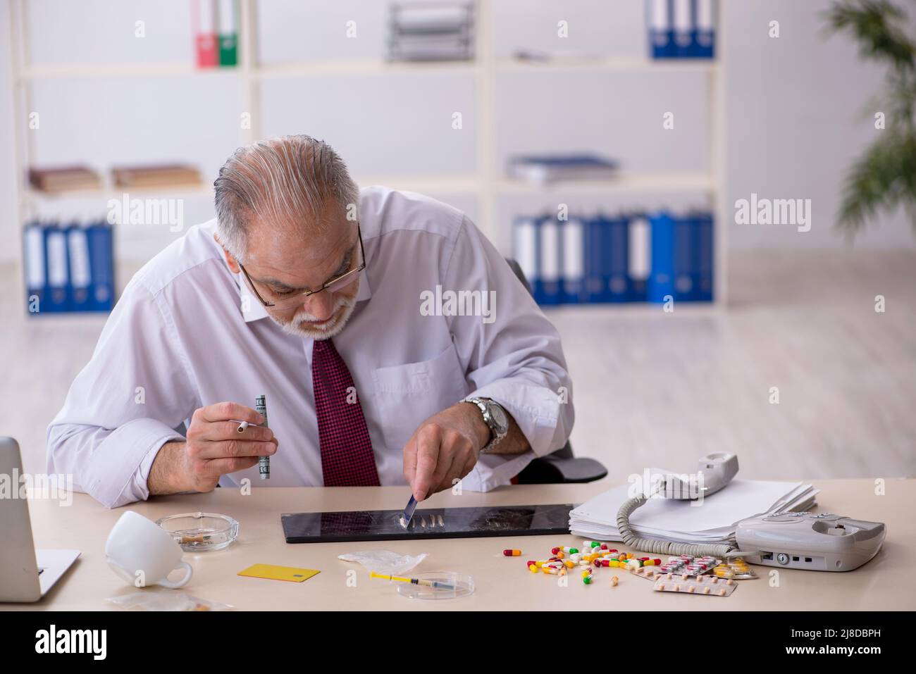 Old male drug addicted employee sitting at workplace Stock Photo - Alamy