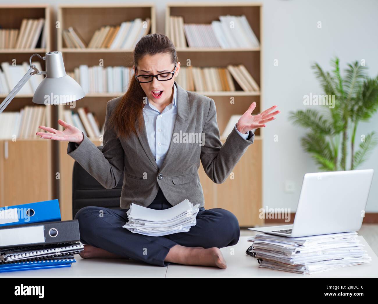 The busy angry businesswoman sitting on the desk in office Stock Photo ...