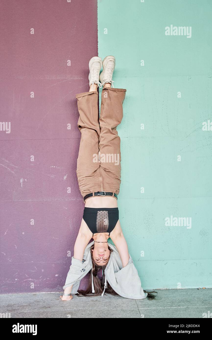 Full length powerful woman in casual wear performing handstand near ...