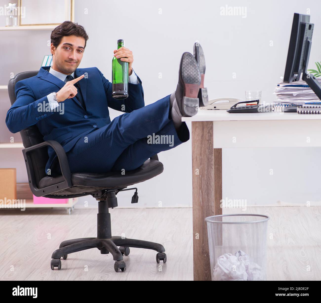 The young businessman employee drinking in the office at desk Stock ...