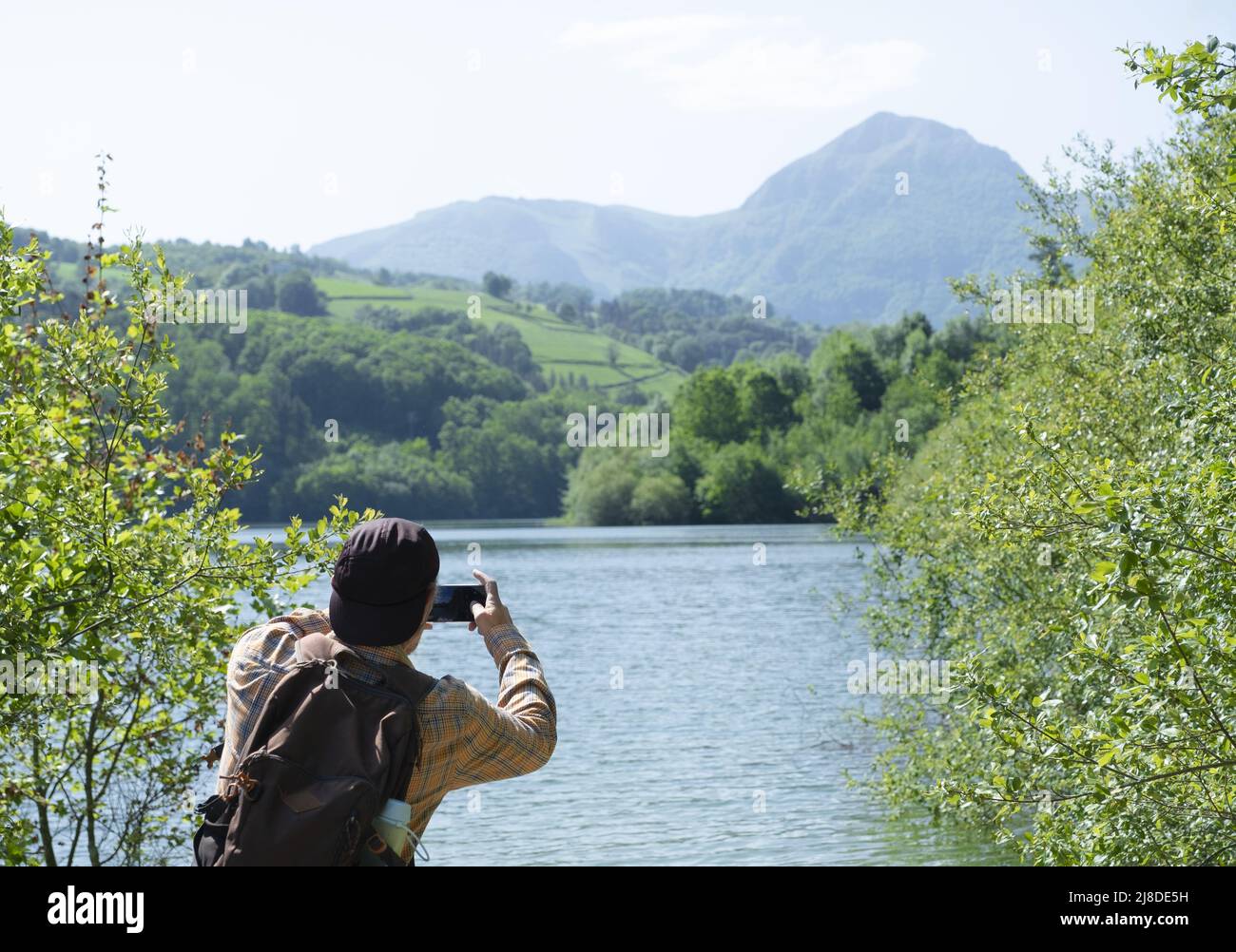 Backpacking traveler photographing the lake and the mountain Stock ...
