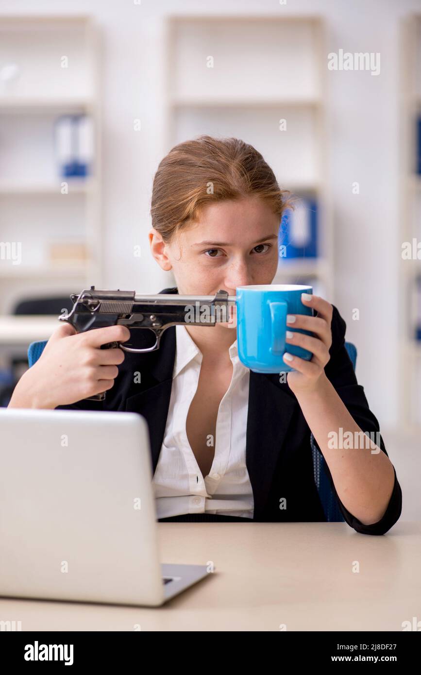Female employee holding gun at workplace Stock Photo - Alamy
