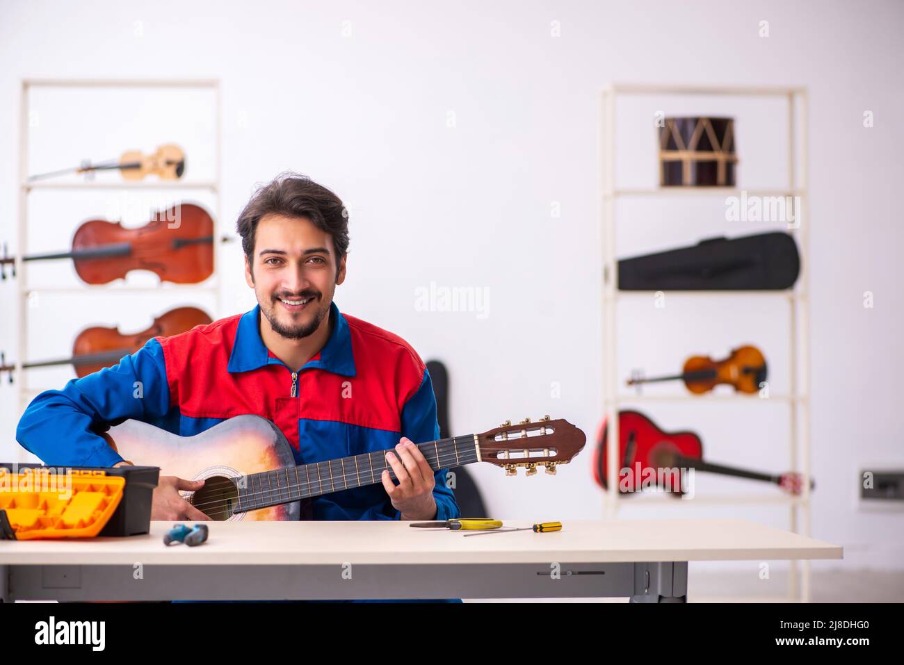 Young repairman repairing musical instruments at workplace Stock Photo ...