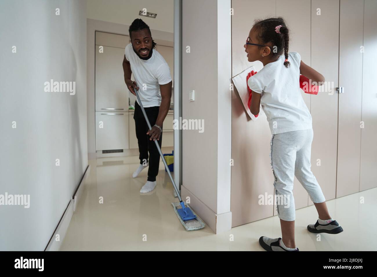 Adult african american man mopping floor in room next to daughter Stock ...