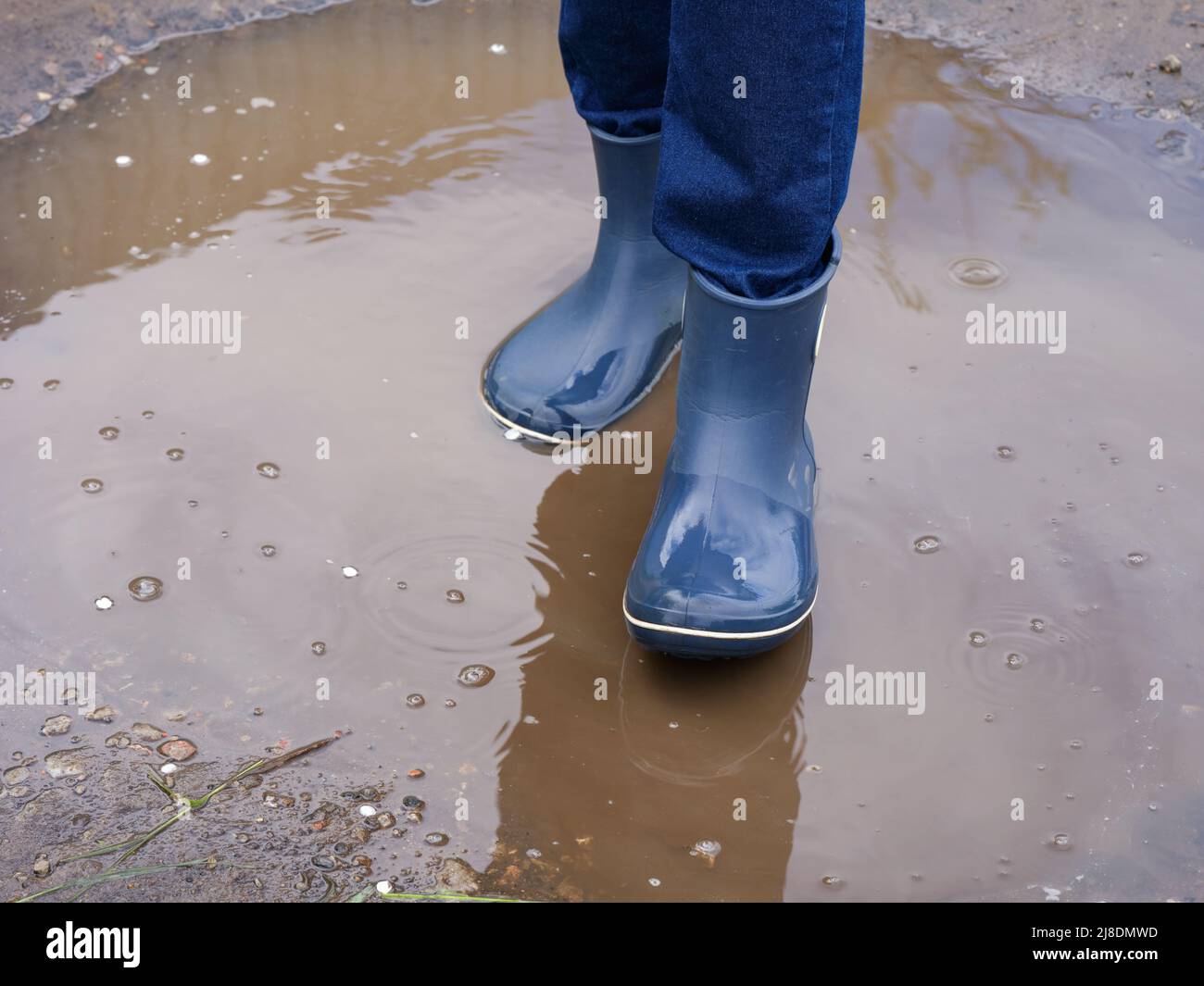 A person in boots standing in a muddy puddle. Close up Stock Photo - Alamy
