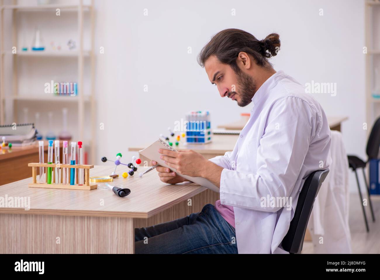 Young chemist sitting at the desk in the classroom Stock Photo - Alamy