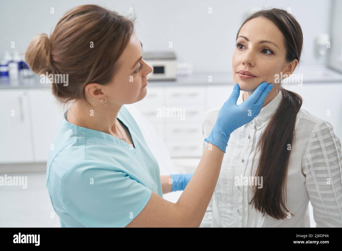 Doctor checking woman face skin in cosmetology clinic Stock Photo - Alamy