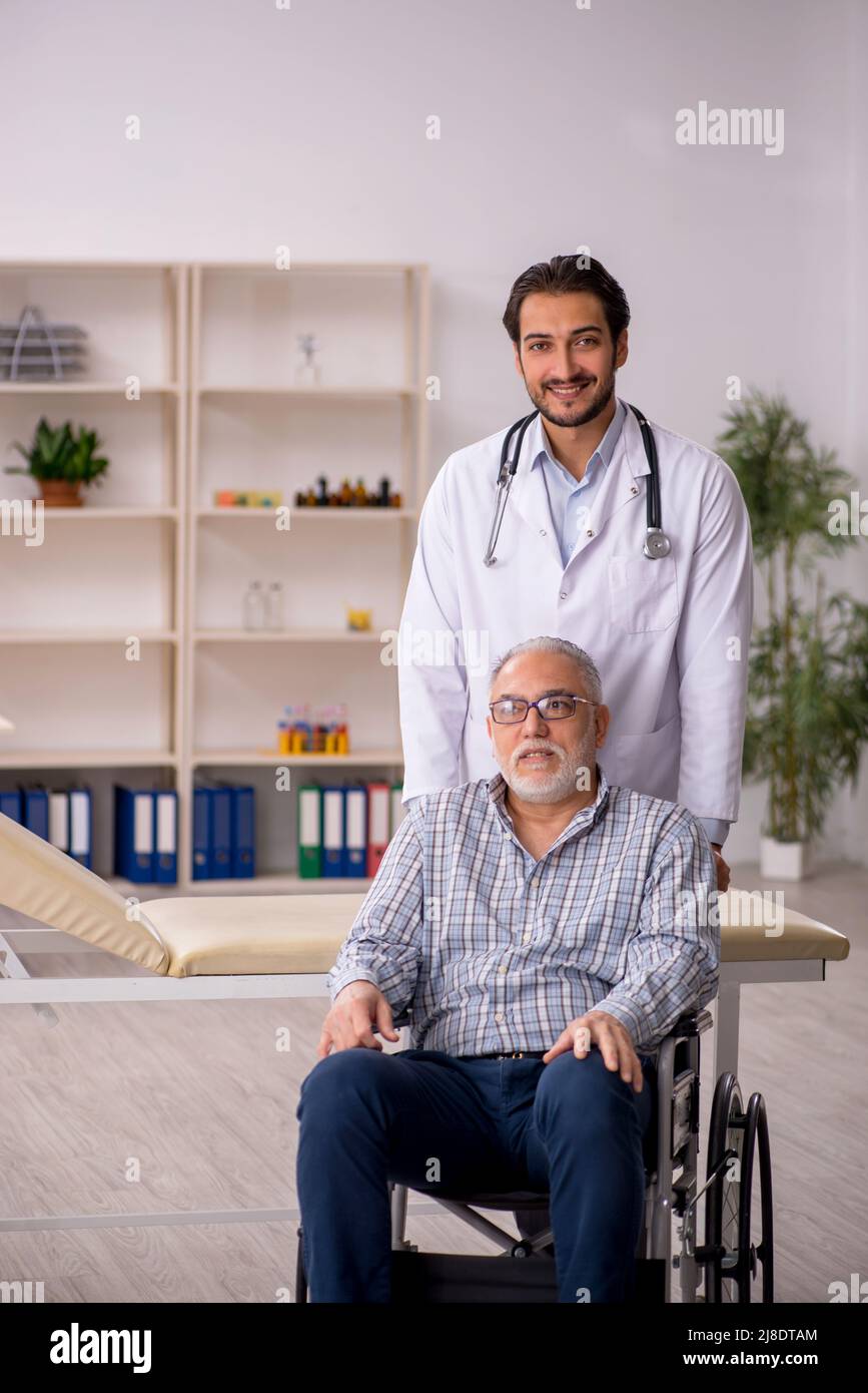 Old male patient in wheelchair visiting young male doctor Stock Photo ...