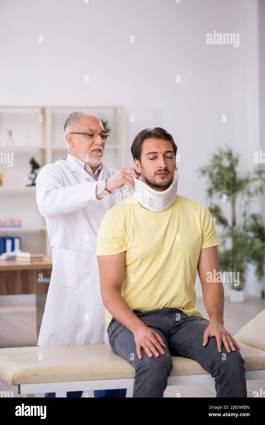 Young neck injured patient visiting old male doctor Stock Photo - Alamy