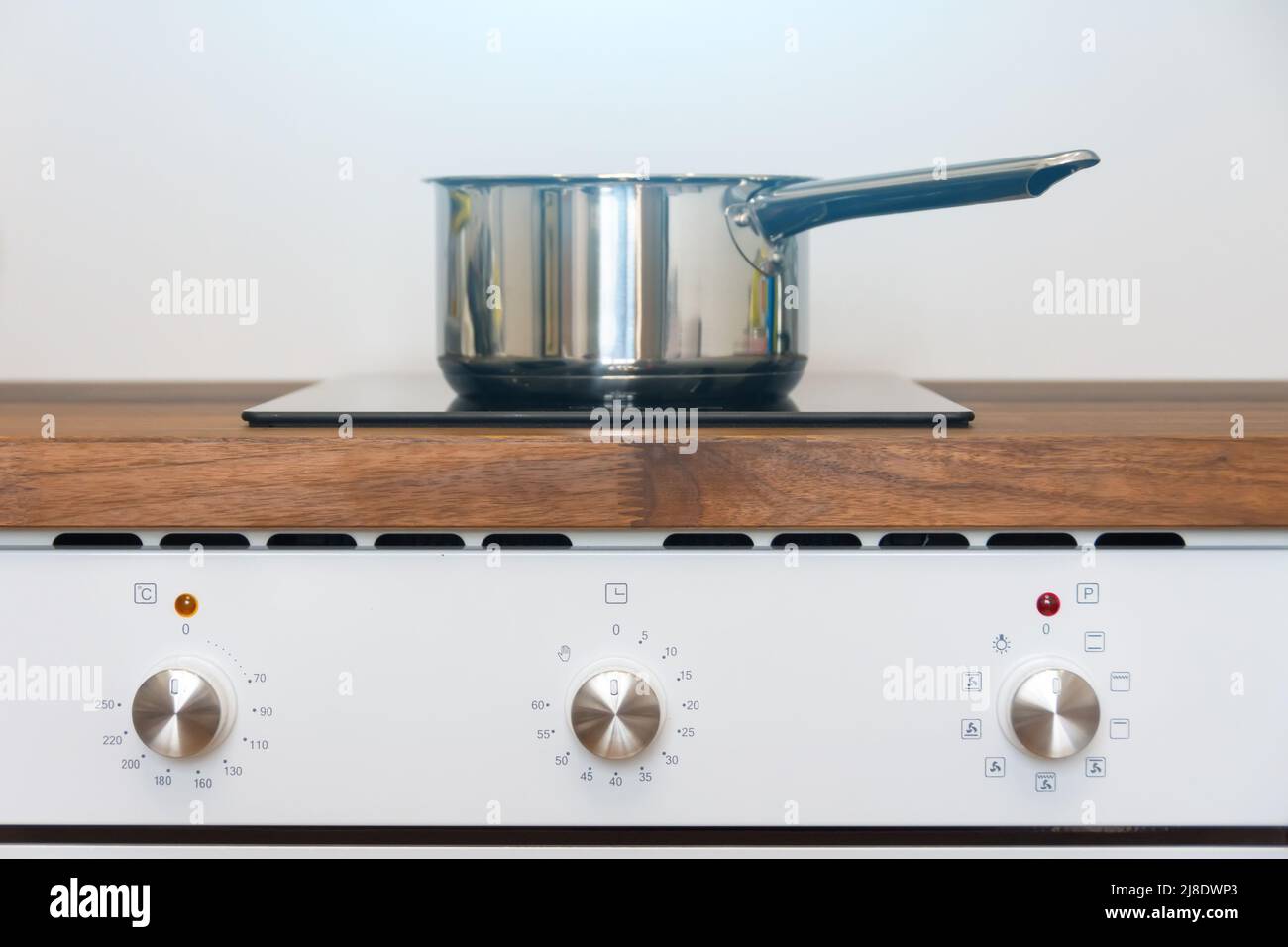 Pot ladle on induction cooker built into wood kitchen worktop view of ...