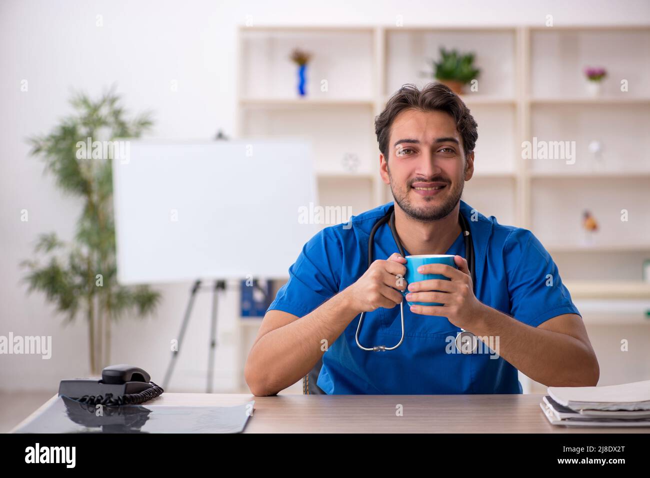 Young doctor drinking coffee during break Stock Photo - Alamy